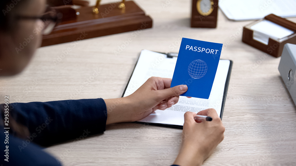 Employee signing deportation document holding blue passport ...