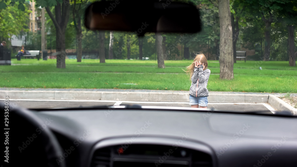 Scared little girl covering face, terrified by driving car, road safety ...
