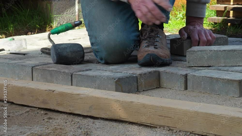 Builder is laying paving tile. Construction workers laying concrete ...