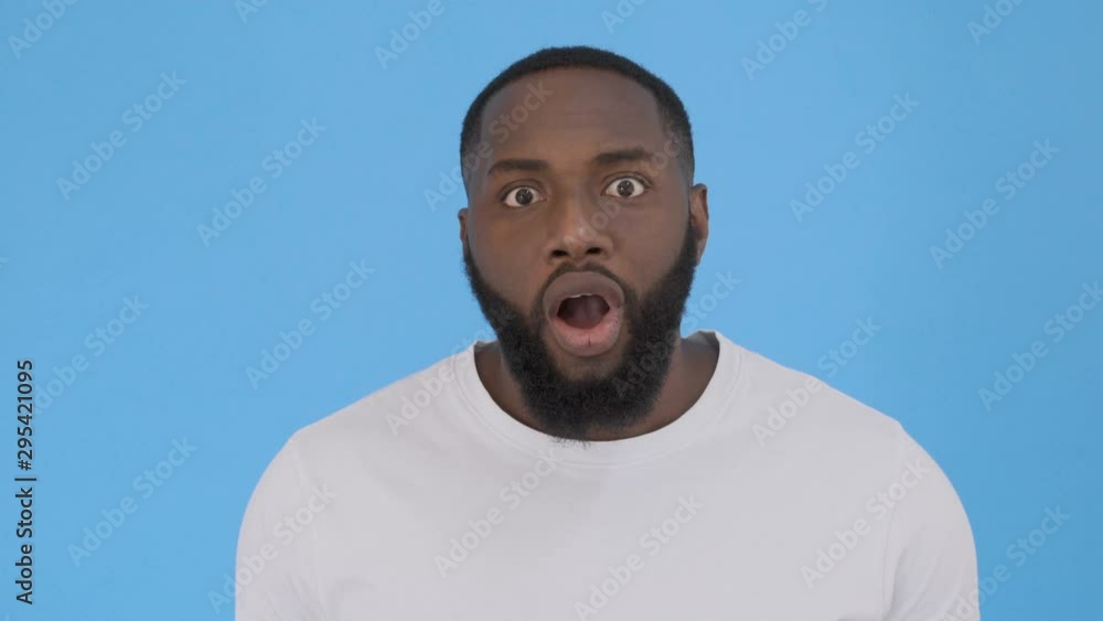 Surprised dark skinned African American male keeps hands on cheeks ...