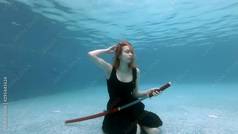 Video Stock A young girl poses underwater at the bottom of a pool with ...