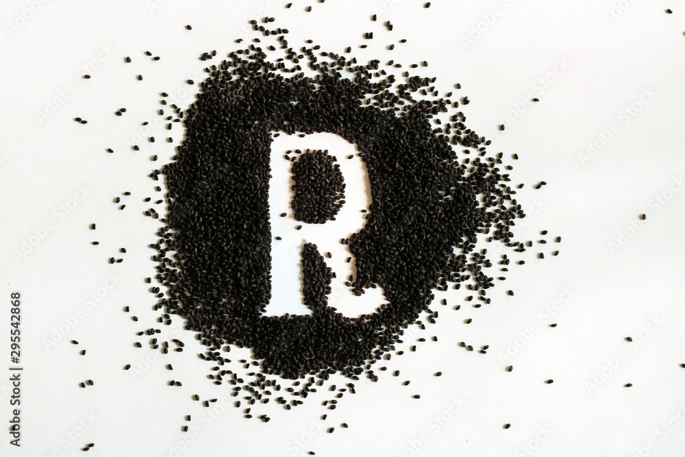 Handful of sweet basil black seeds, letter R uppercase of English ...