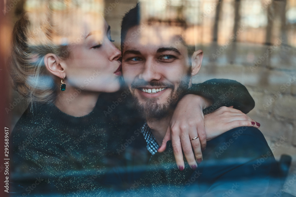 Pretty woman is kissing her smiling man, wich is watching through the ...