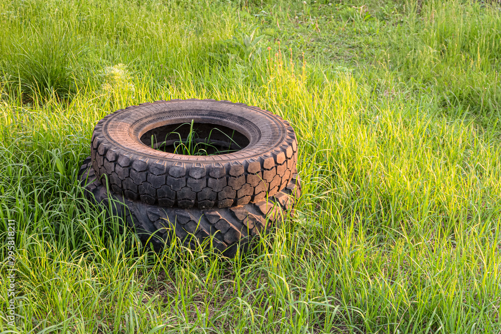 Car rubber tires thrown into a stack on green grass. Nono-ecological ...