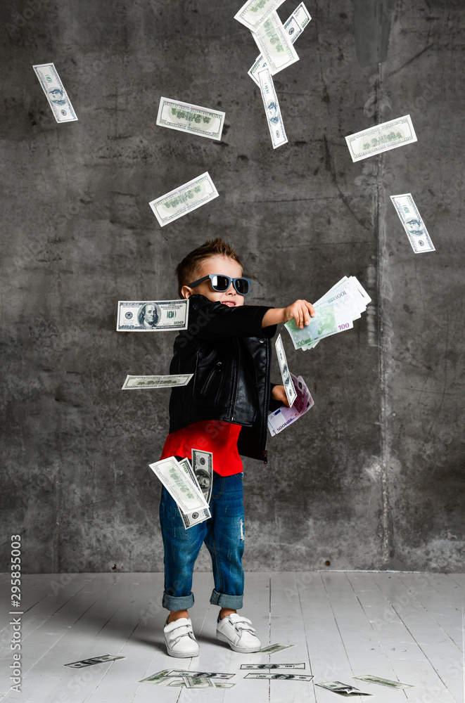 Kid boy millionaire in leather jacket and jeans is throwing around ...