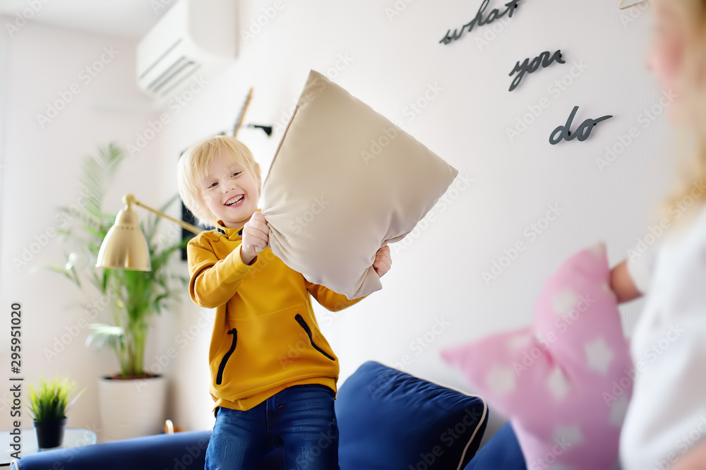Pillow fight. Mischievous preschooler children jumping on a sofa and ...