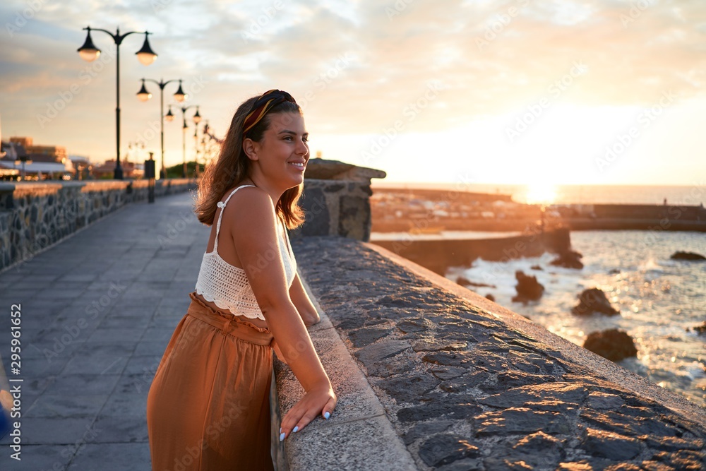 Beautiful young woman walking on beach promenade enjoying ocean view ...