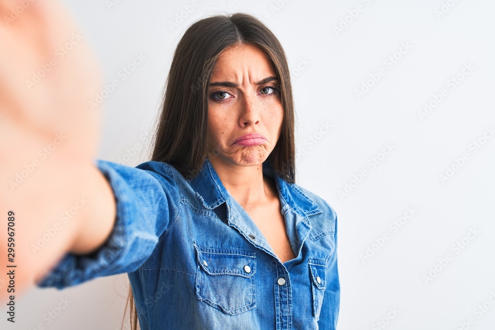 Beautiful woman wearing denim shirt make selfie by camera over isolated ...