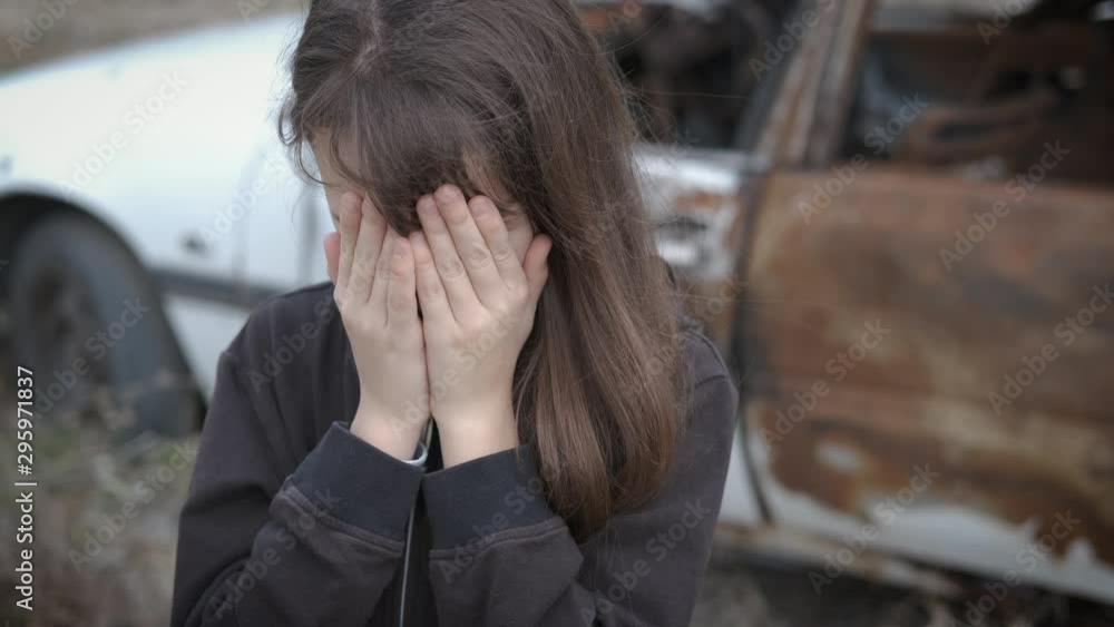 Tearful child. Homeless little girl crying at the junkyard. The child ...
