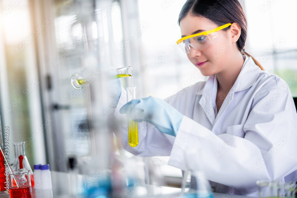 Attractive scientist woman looking chemical sample in flask at ...
