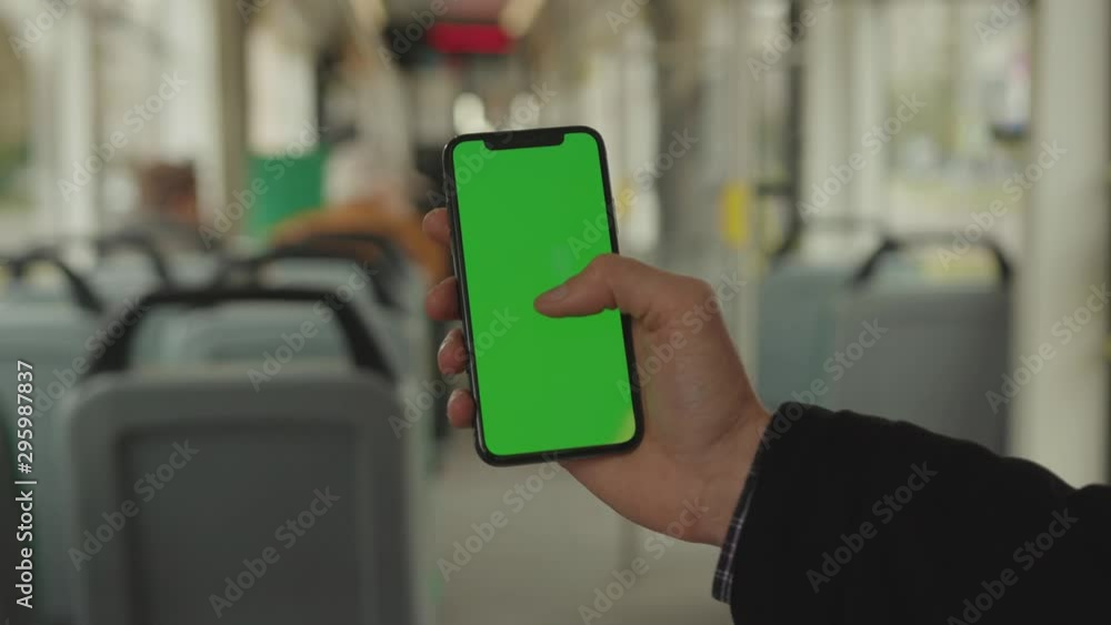 Shot of man young hand uses holding a mobile telephone with a vertical green screen background ...