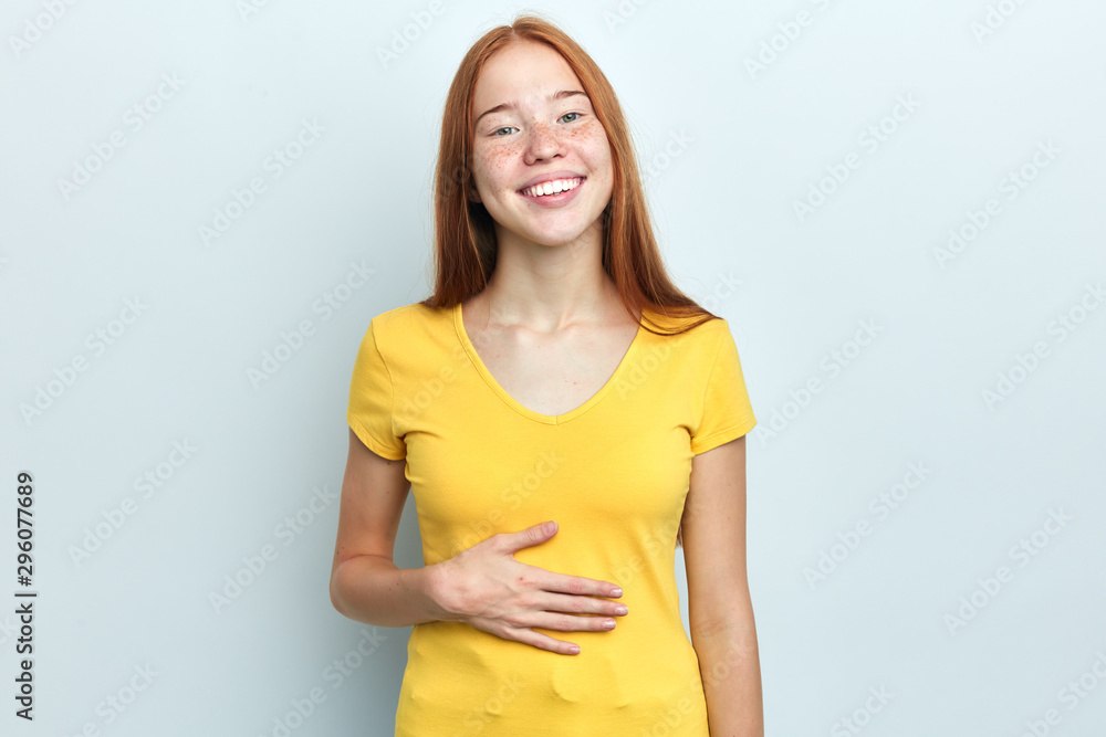 Happy cheerful woman with freckles touching her stomach, close up ...