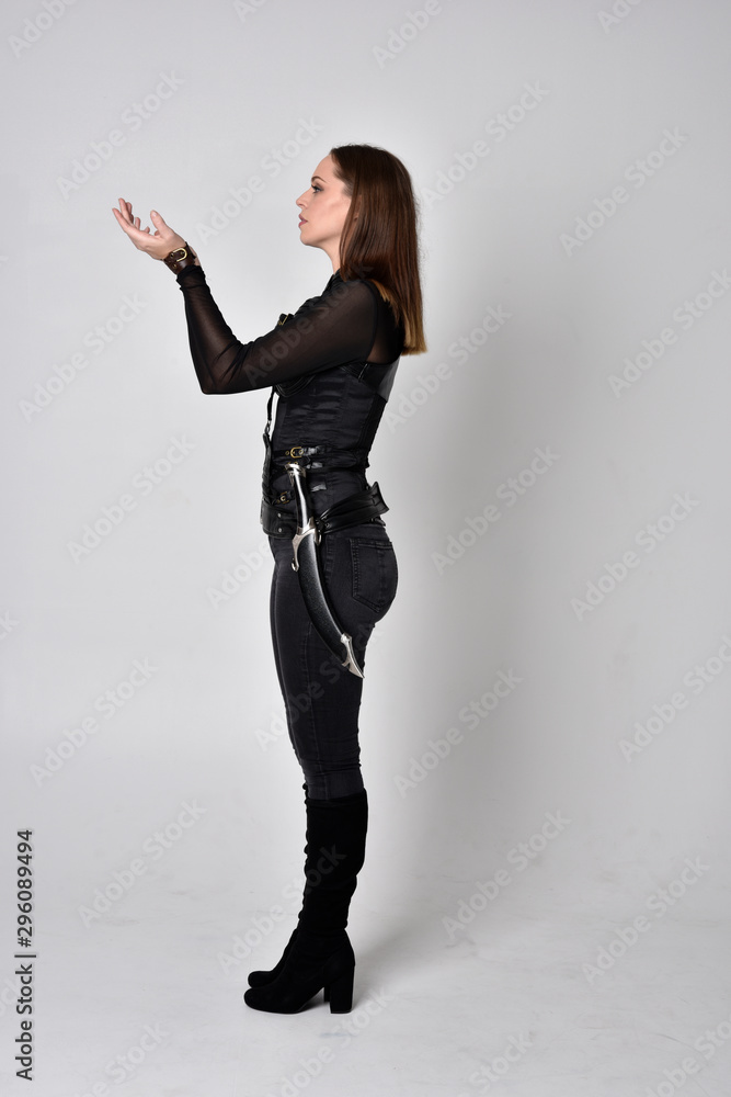 full length portrait of a pretty brunette woman wearing black leather ...