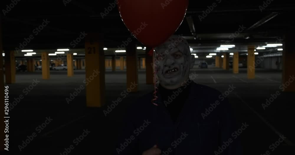 Scary man in creepy leather mask is standing with red ball in dark ...