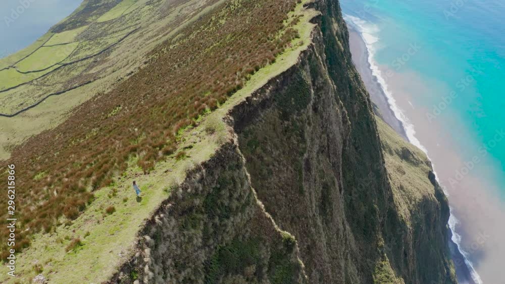 Woman walks along the edge of steep cliff of vast extinct volcano ...