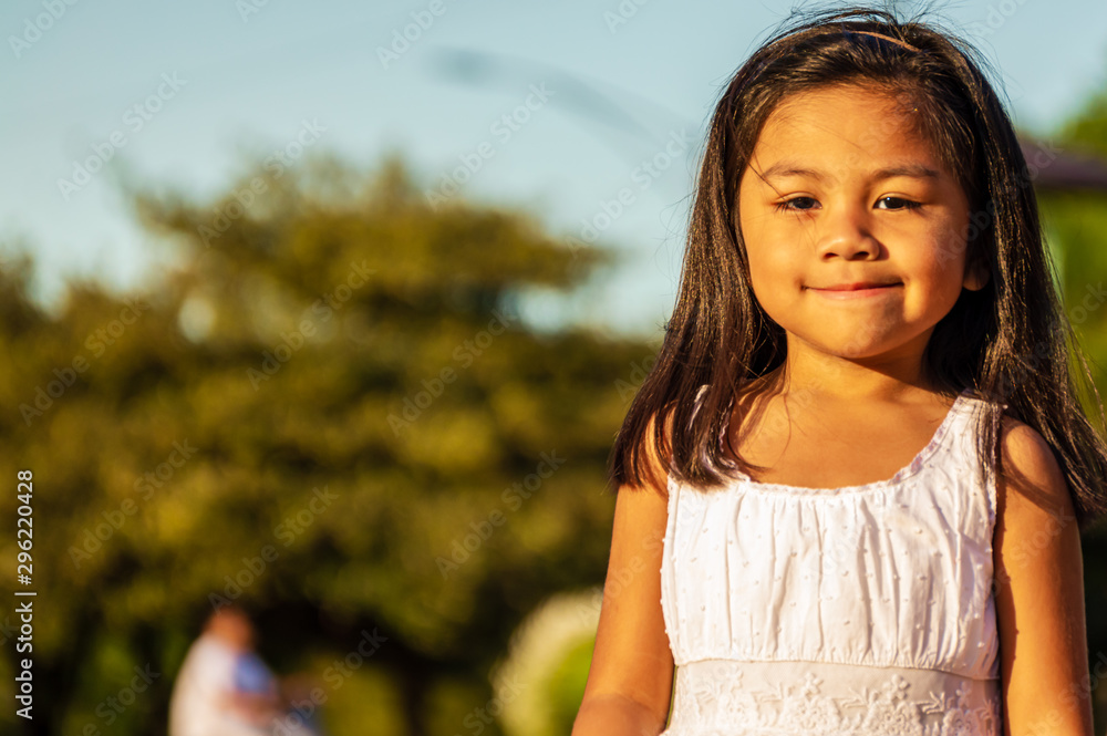 Cute Mexican American girl child is playing in a park in the city ...