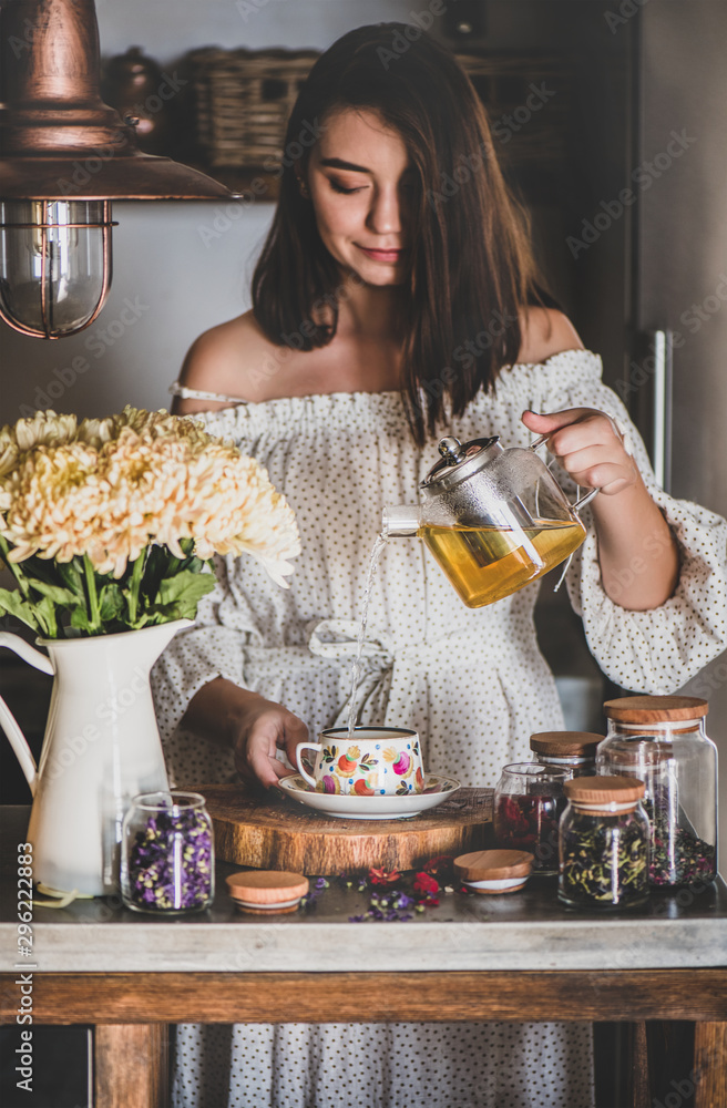 Young smiling caucasian woman with black hair in dress pouring freshly ...