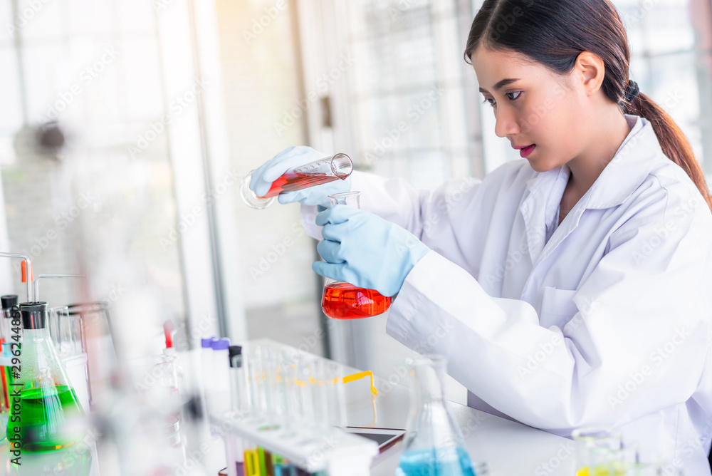 Attractive scientist woman looking chemical sample in flask at ...