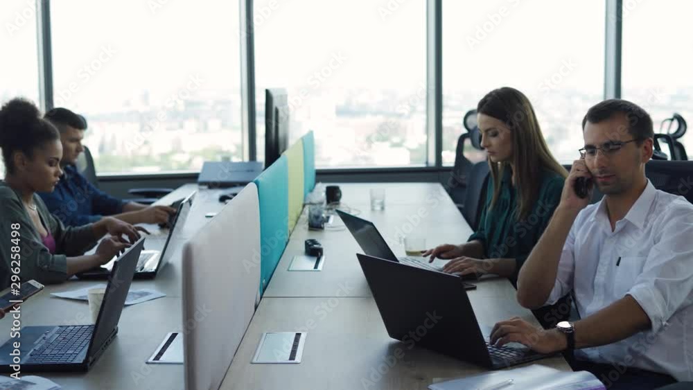 International teamwork in modern office space, people work on the ...