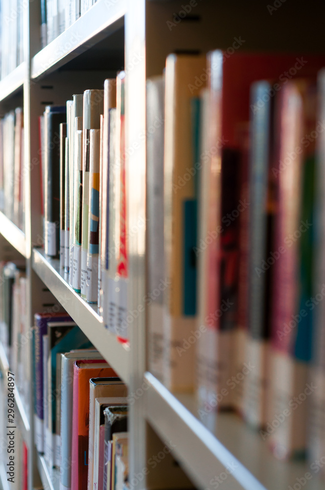 Books on a white bookshelf in a public library room. education ...
