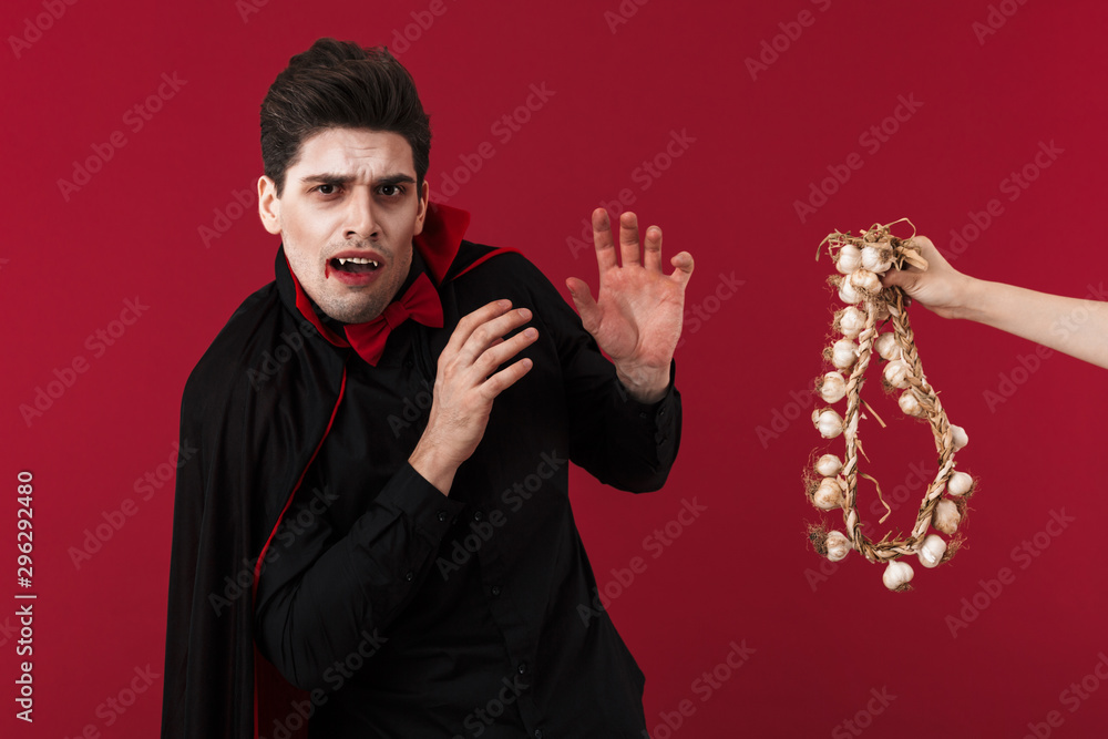 Image of young vampire man in halloween costume being scared of garlic ...