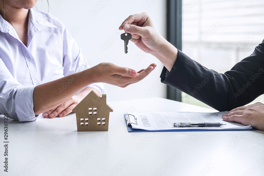Estate agent giving house keys to client after signing agreement ...