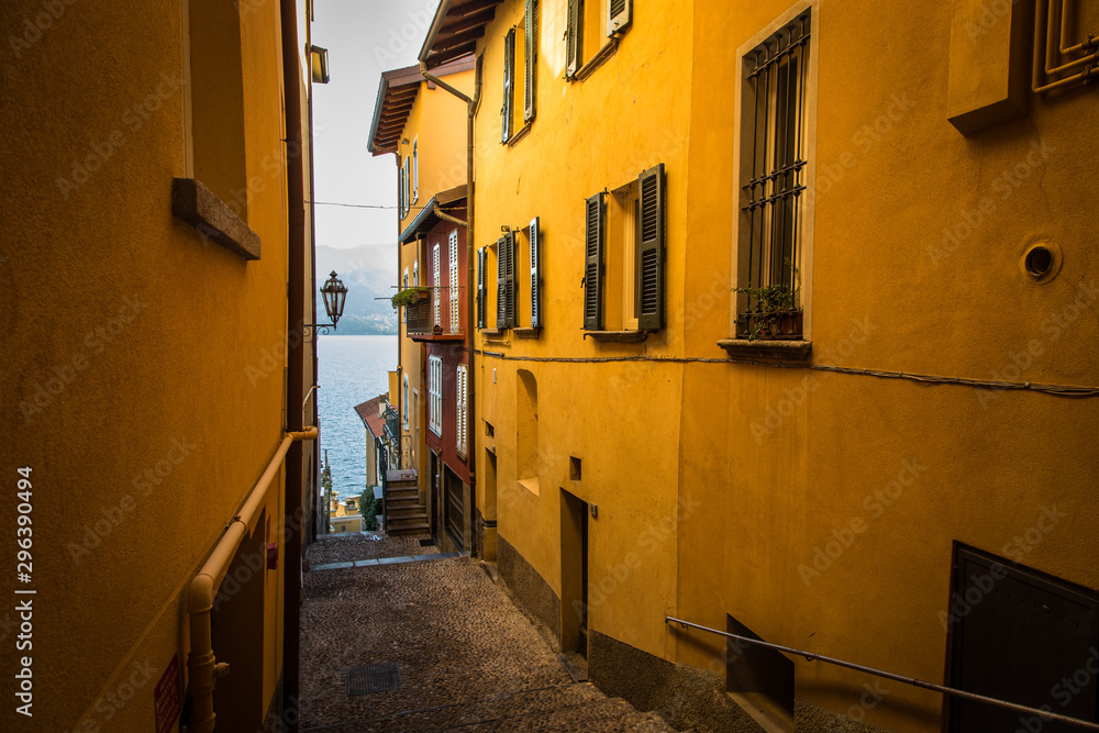 Strada stretta tra case che porta al lago Stock Photo | Adobe Stock