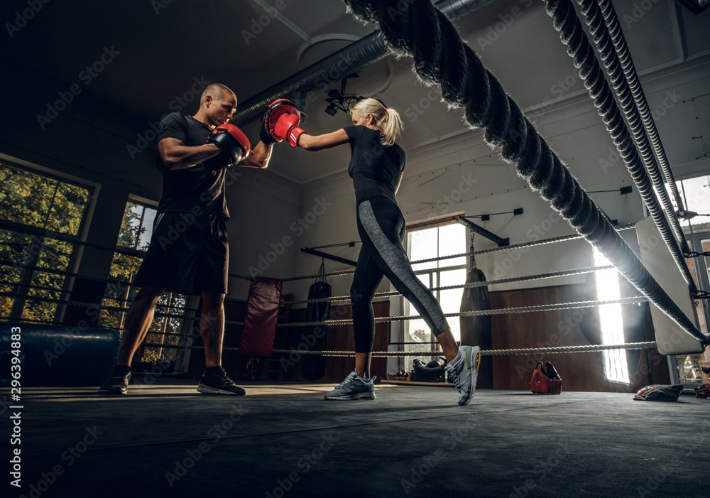 Boxing trainer and his new student have a sparring on the ring wearing ...