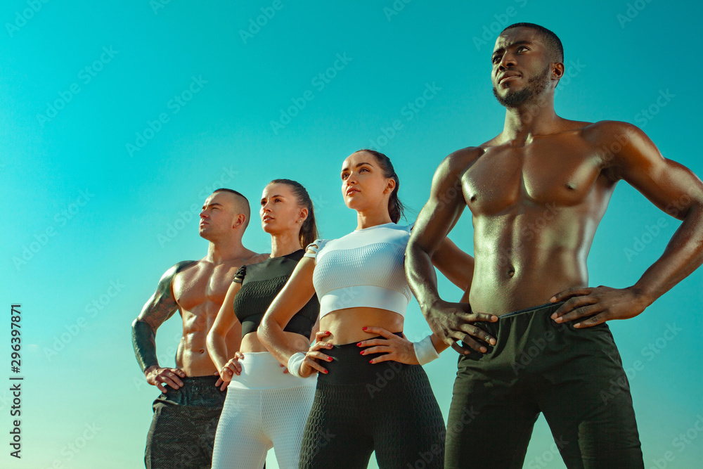 Group of four young sportsmens women and men, fit athletes are standing ...
