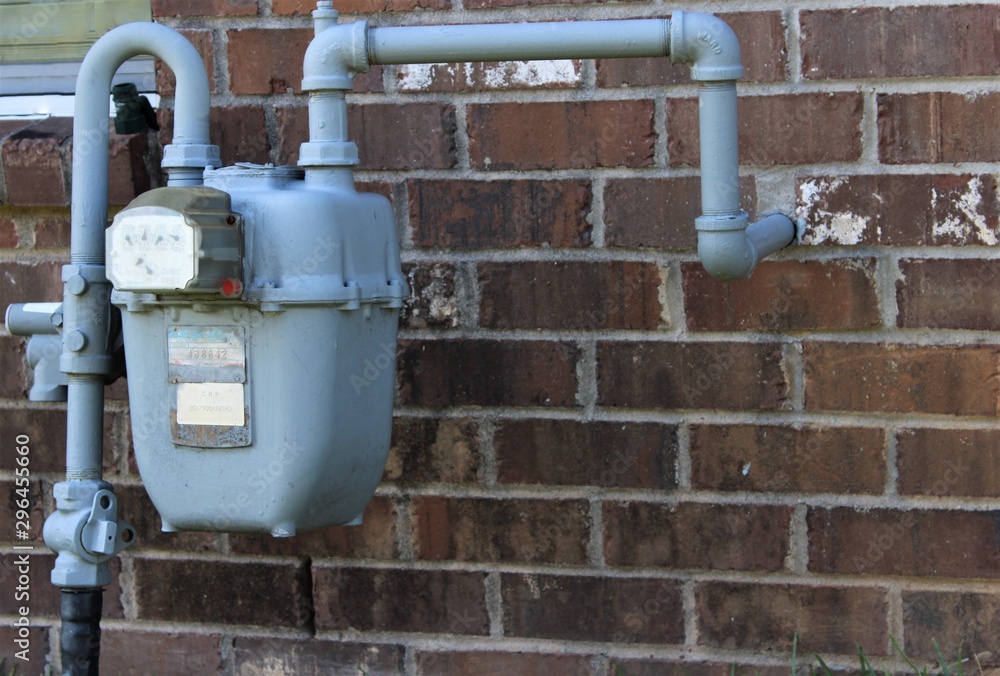 Foto de Electric meter with pipes and valves on the side of a house do ...