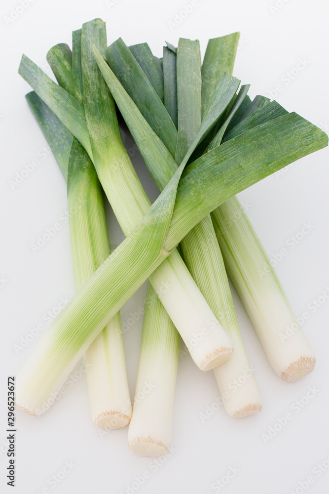 Bunch of fresh full leeks in a white background. Green and white leeks ...