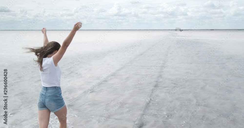 Girl in salt resort walks on shallow, feet ankle-deep in water, sunken ...