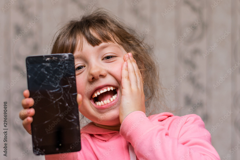 Portrait of a cheerful little girl with a mobile phone. The child broke ...