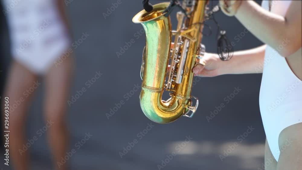 Attractive saxophonist lady is playing on saxophone near pool at beach ...