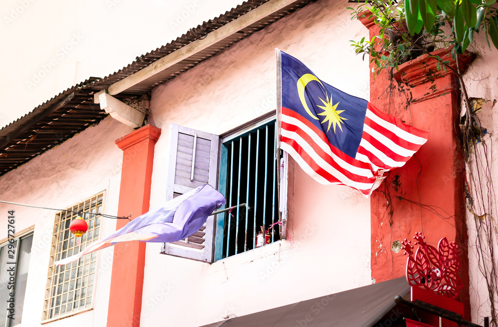 The flag of Malaysia in a window of a traditional old rustic building ...