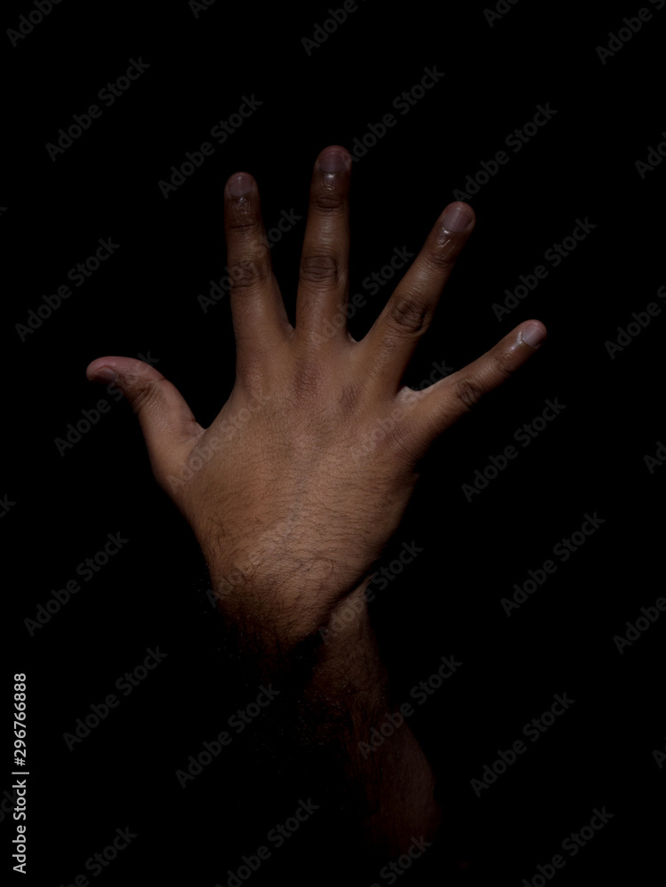 Low key photo of a brown man showing the back of his hand with his ...