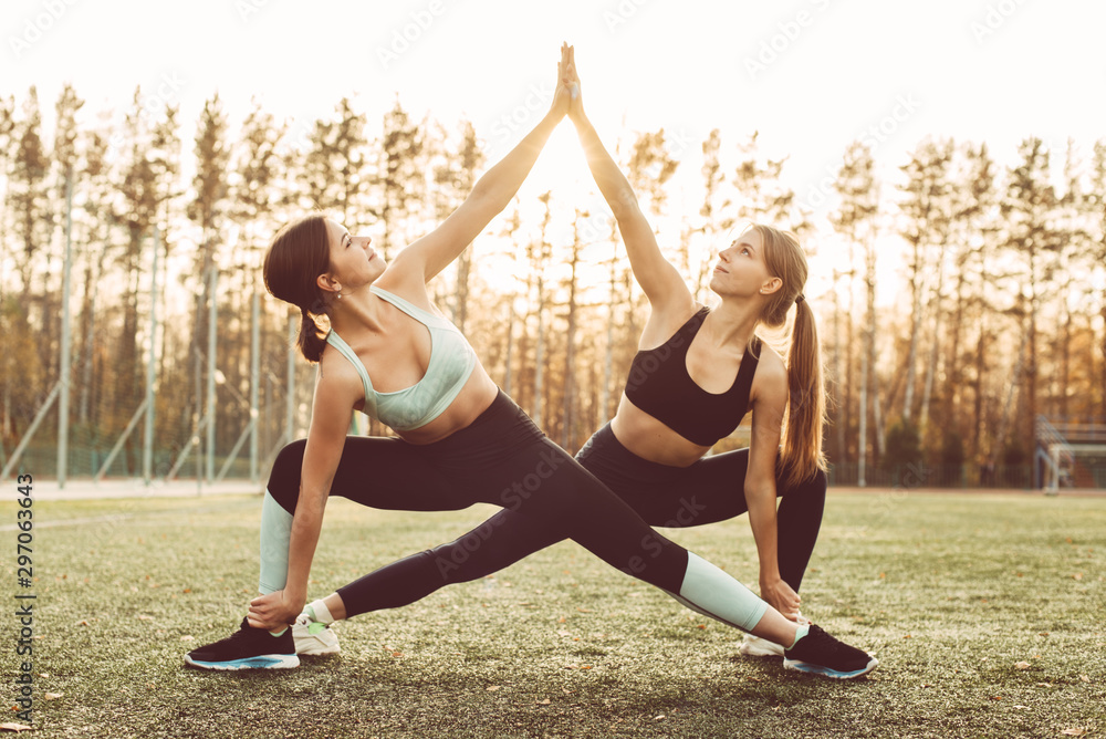 Paired yoga classes in nature. Two young women doing yoga poses at the ...