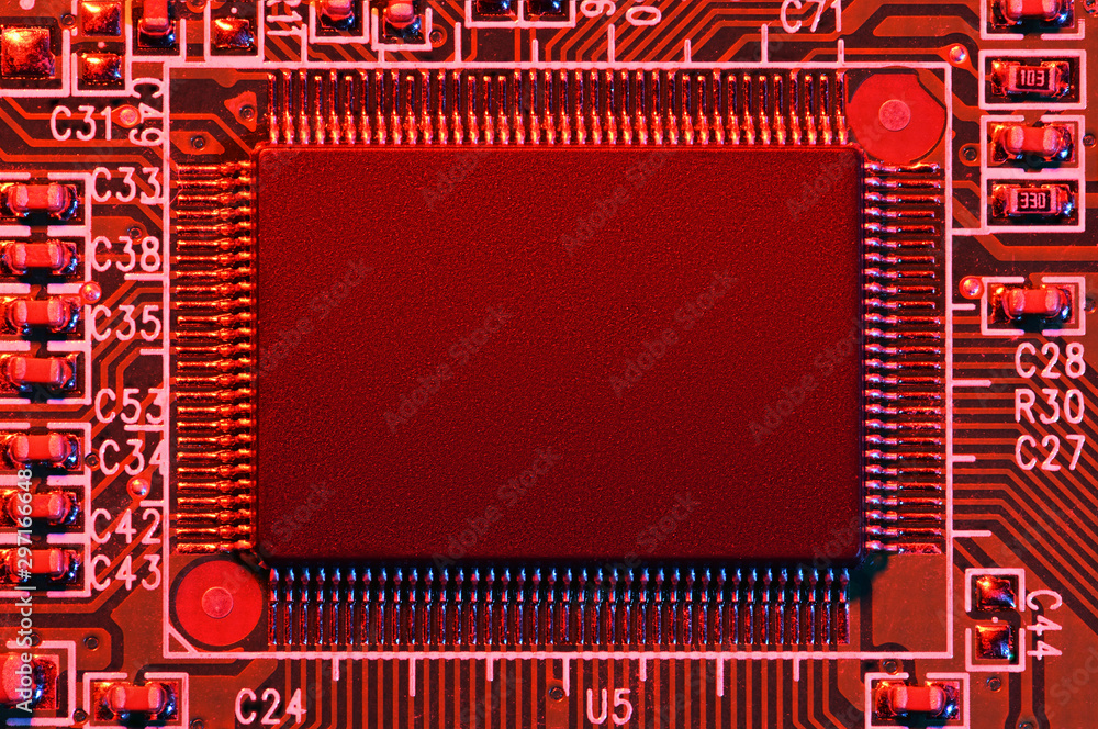 printed circuit board and microchip, or cpu, in red light closeup ...