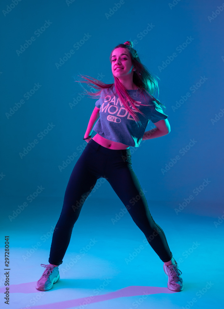 Young stylish girl dancing zumba in the Studio on a colored neon ...