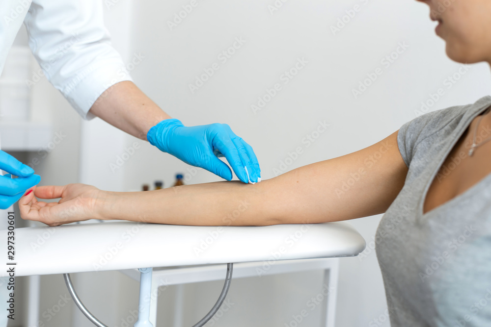 A nurse wipes a patients hand with a cotton pad soaked in an antiseptic ...