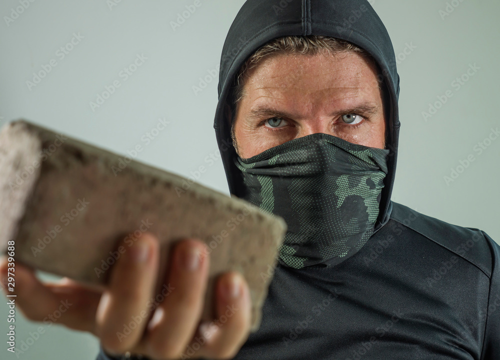 young man as radical and aggressive anarchist rioter holding brick ...