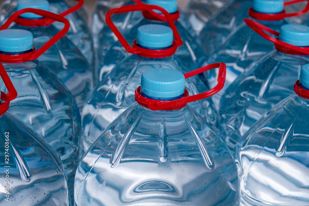 5 liter bottles with drinking water. Blue covers and red handles ...