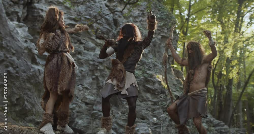 Happy tribe of cavemen neanderthals wearing animal skin holding weapon ...