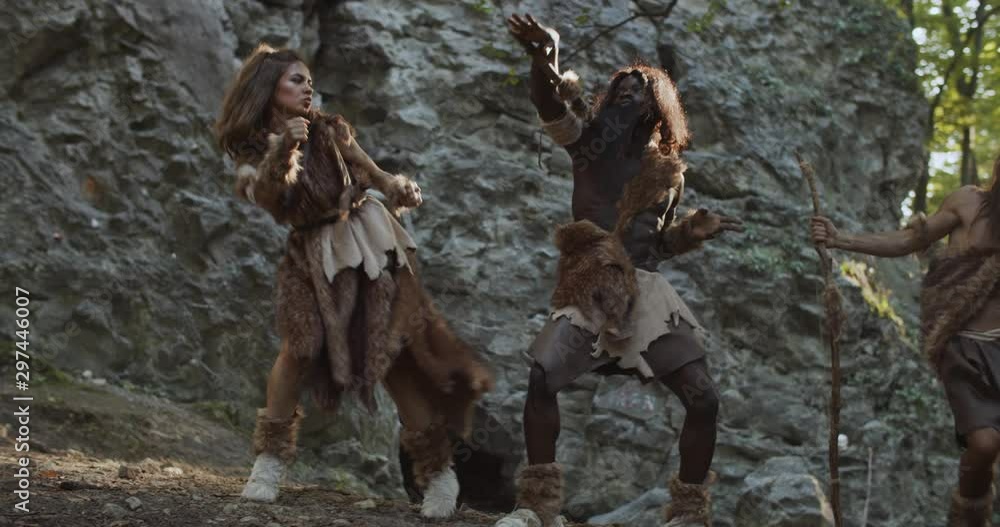 Funny tribe of cavemen neanderthals wearing animal skin holding weapon ...