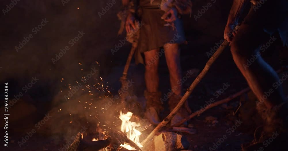 Vidéo Stock In dark two cavemen stand by the fire at night in a cave ...