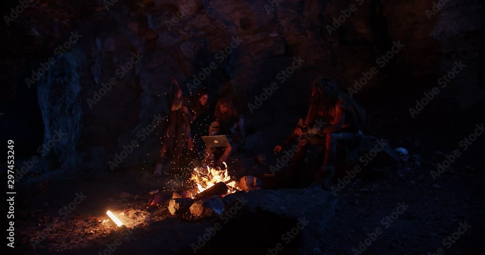 Close up neanderthals wearing animal skin use tablet computer sitting ...