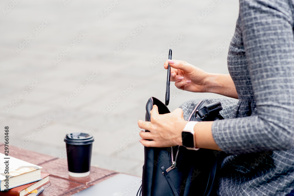 Student girl puts ballpoint pen into black backpack on bench. Girl's ...
