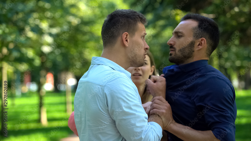 Angry boyfriend pushing man fighting outdoors, girlfriend trying to ...