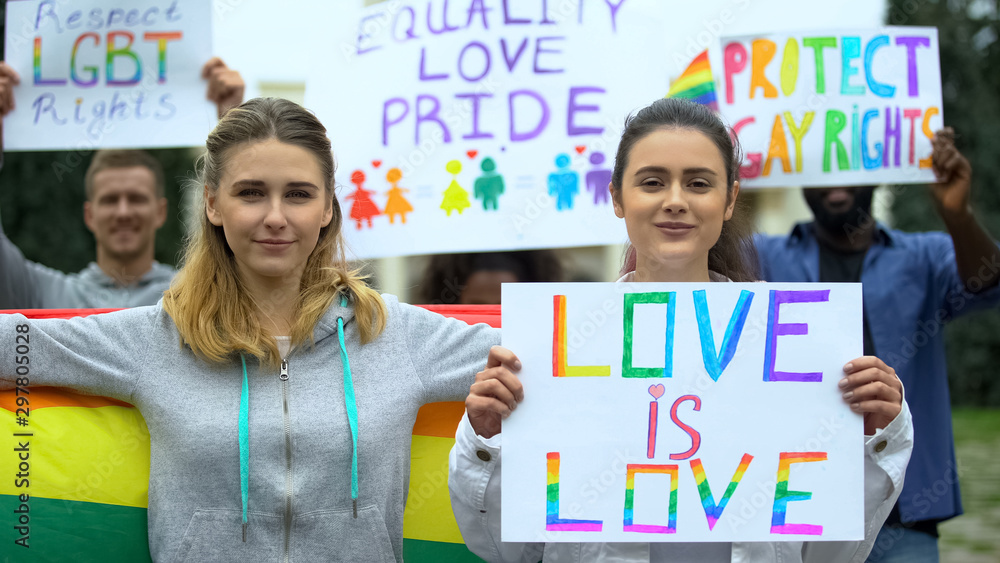 Foto de Positive crowd raising rainbow symbols and posters for LGBT ...