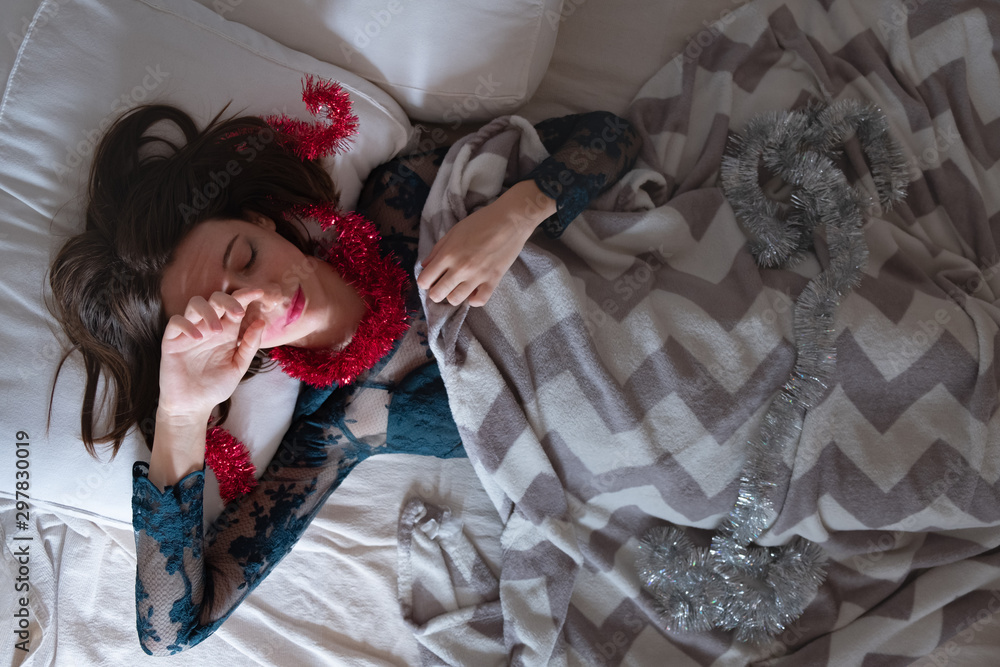 Waking up after a big party. Woman in bed lit by morning light from the ...
